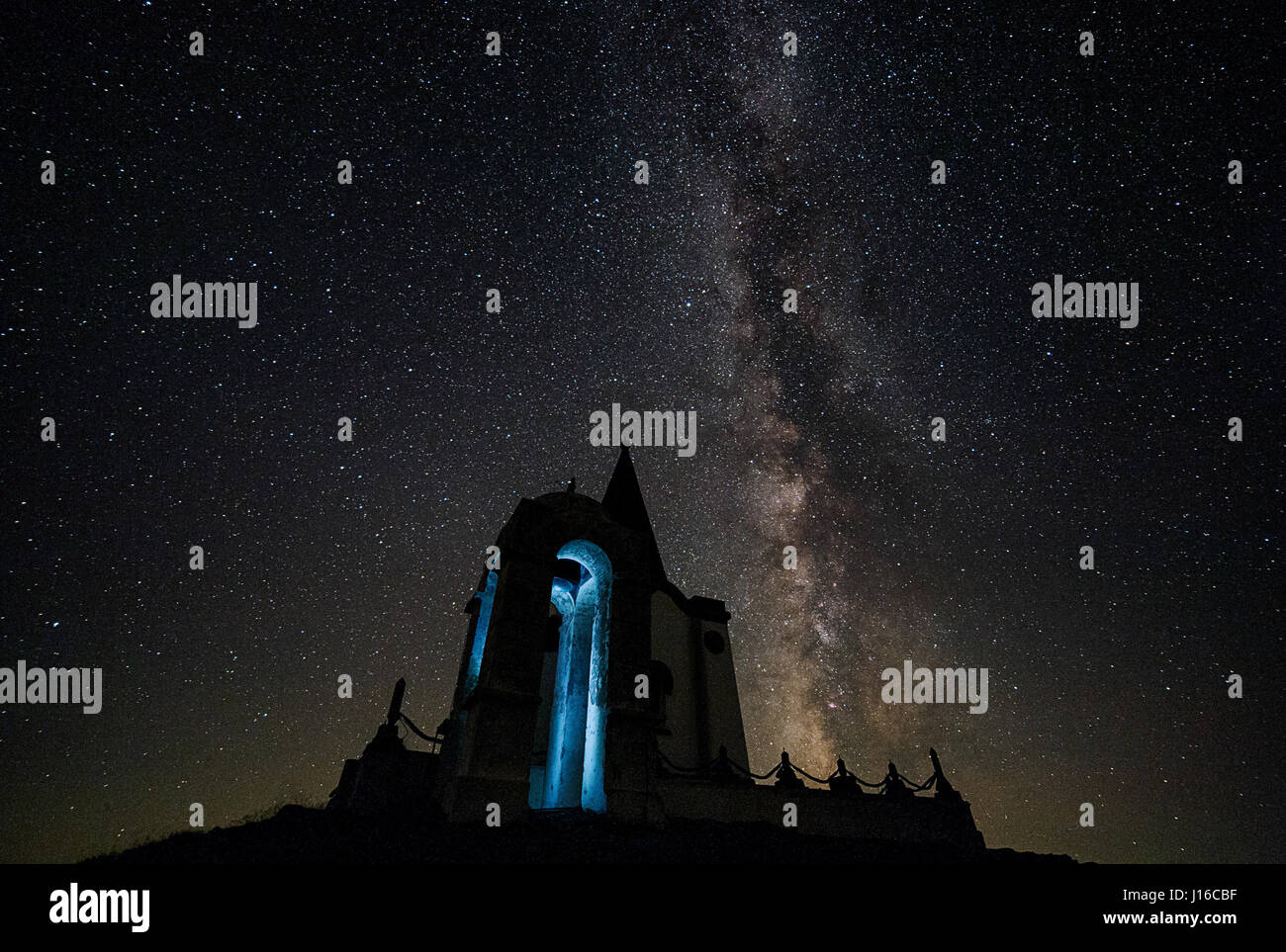 A ruined church is lit up against the backdrop of th Milky Way. A ...