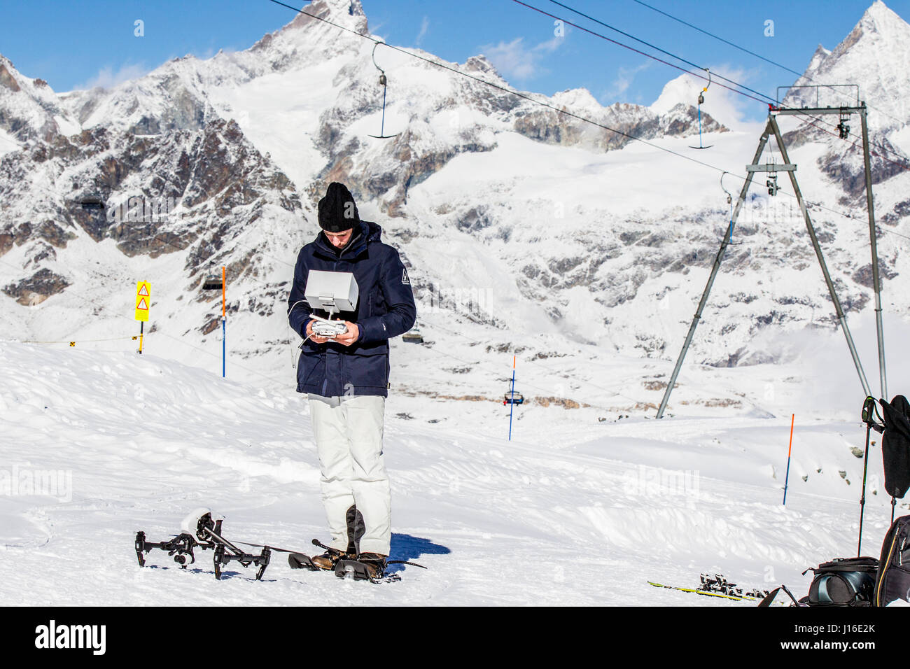 Drone operator standing on snow under ski lift in mountains Stock Photo ...