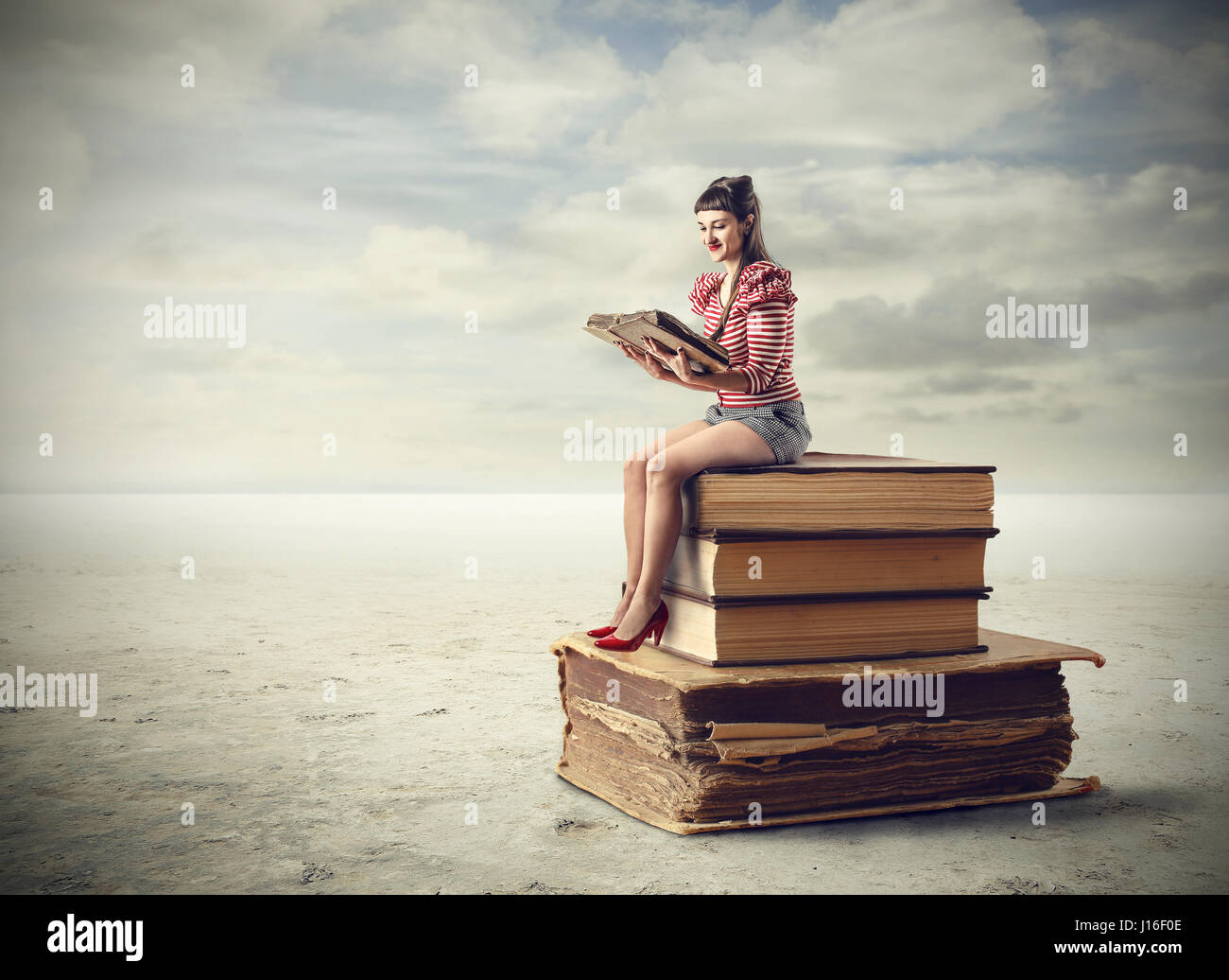 Woman sitting on huge books Stock Photo - Alamy