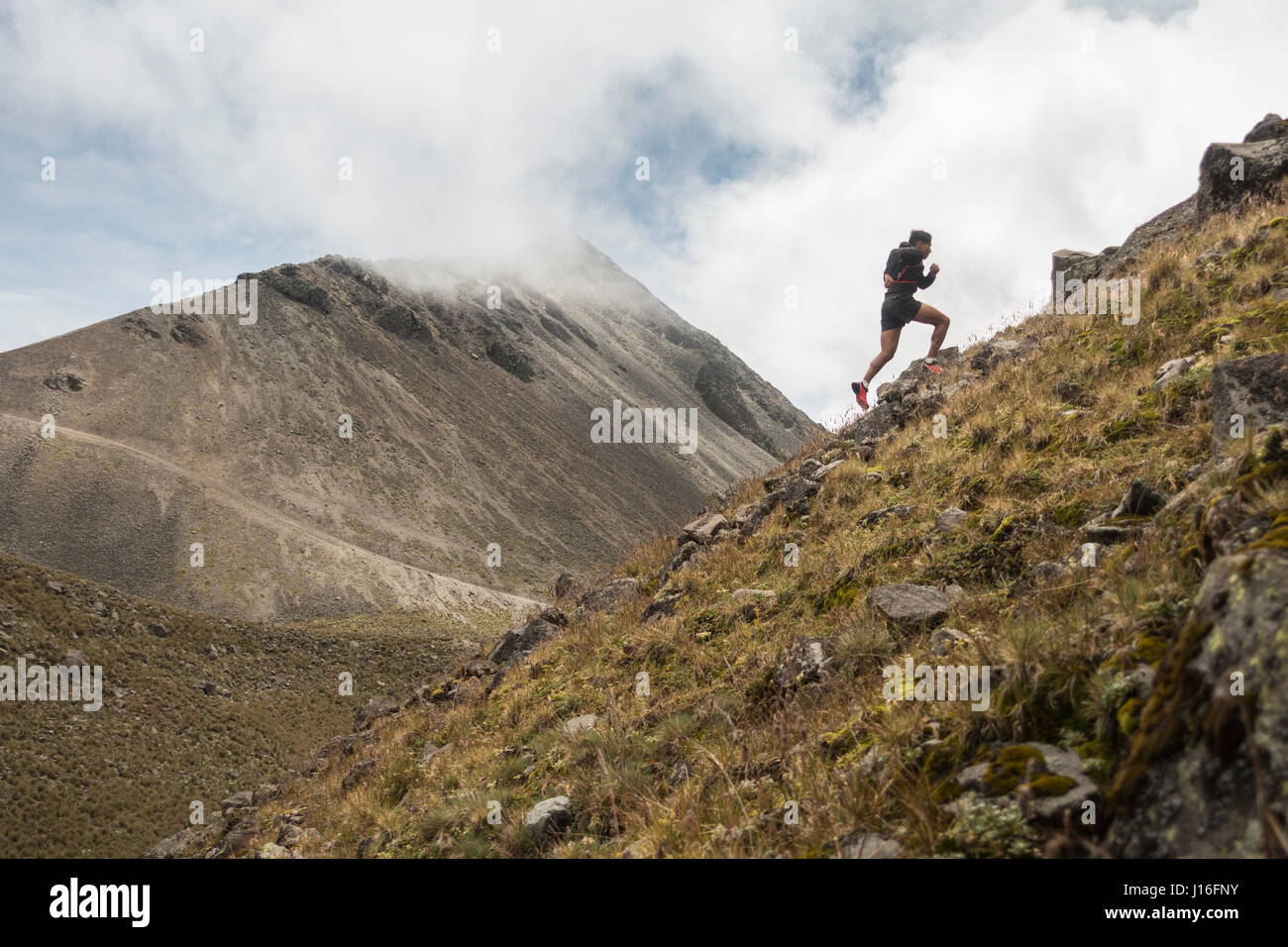 A trail runner climbing a steep slope at Nevado de Toluca volcano in ...