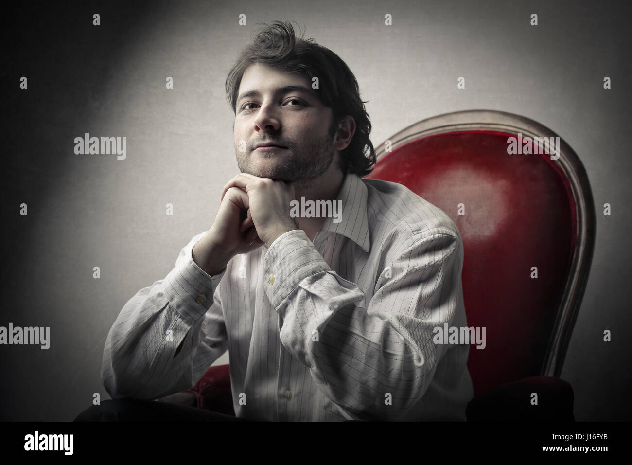 Bearded man sitting on arm chair Stock Photo - Alamy