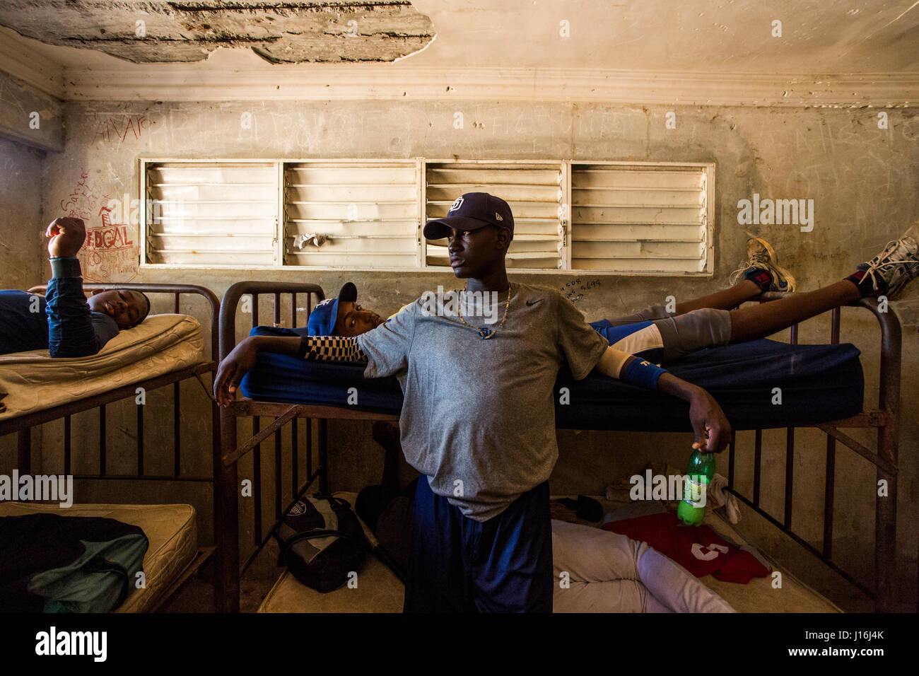A Young Man Leans Against A Bunk Bed In A Concrete Dorm Room Stock ...