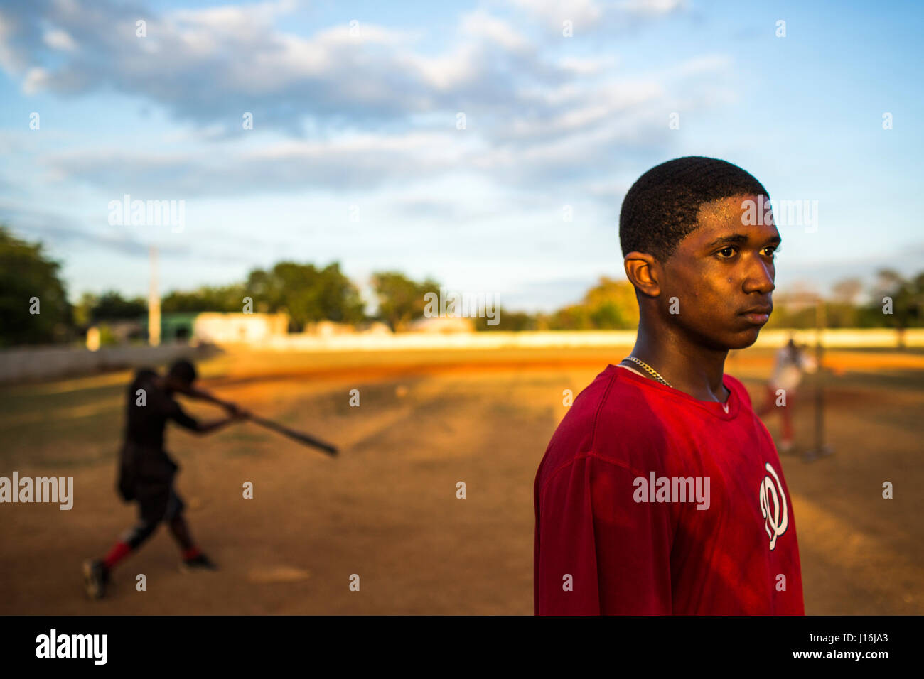 A Young Man In A Red Jersey Looks Into The Distance While Another ...