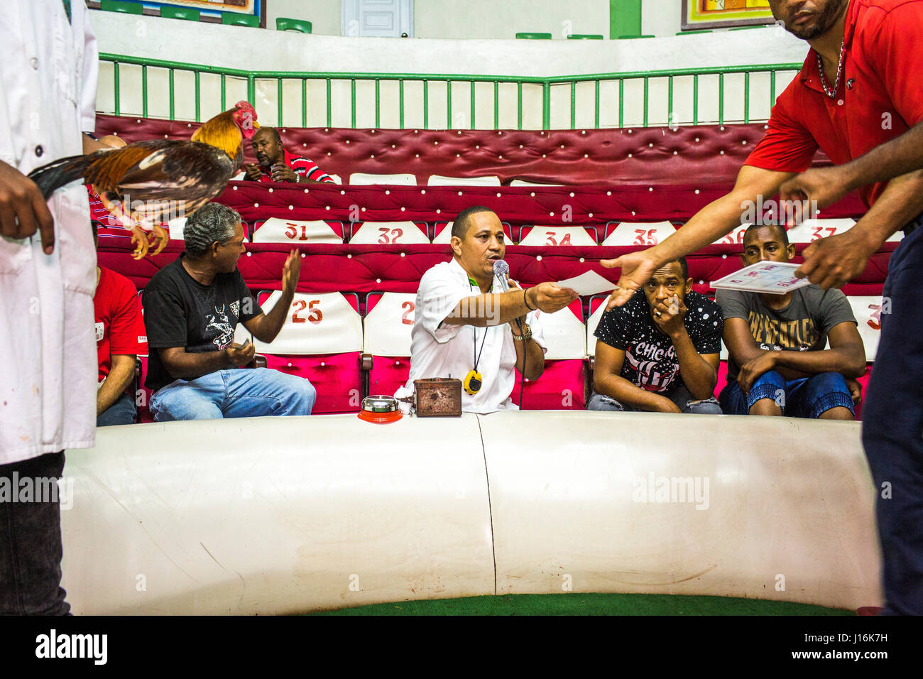 A Man Seated In A Small Red And White Arena Takes Money From A Another ...