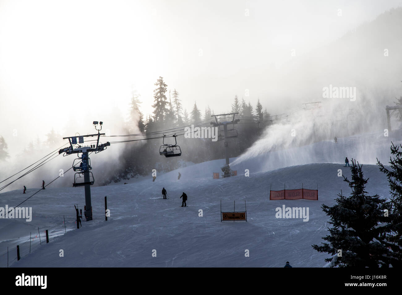 Skiers near a snow cannon which is making powder snow, Whistler, Canada ...