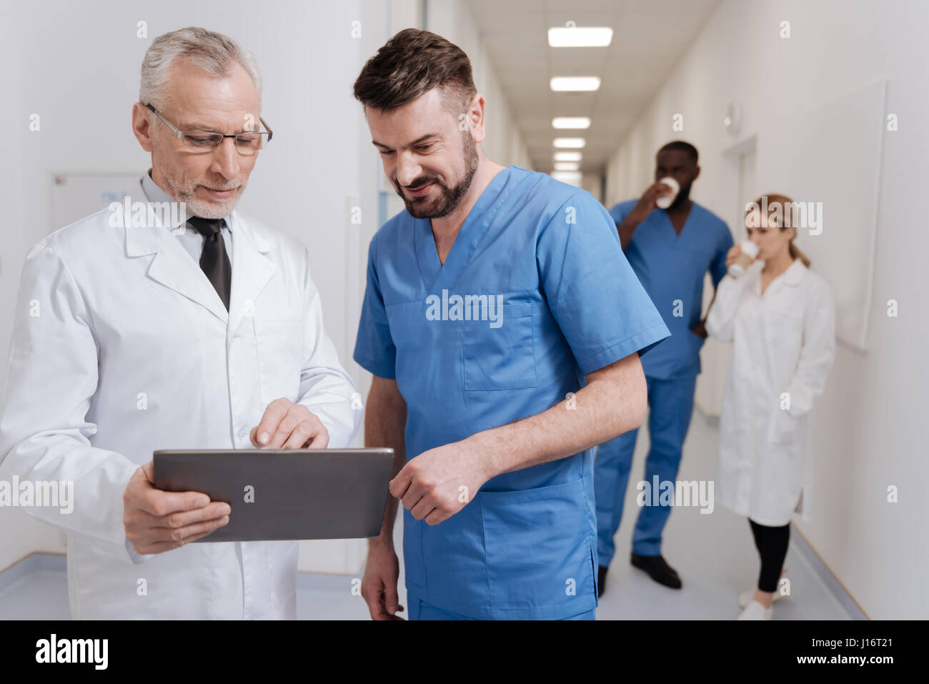 Optimistic colleagues using modern device in the hospital Stock Photo ...