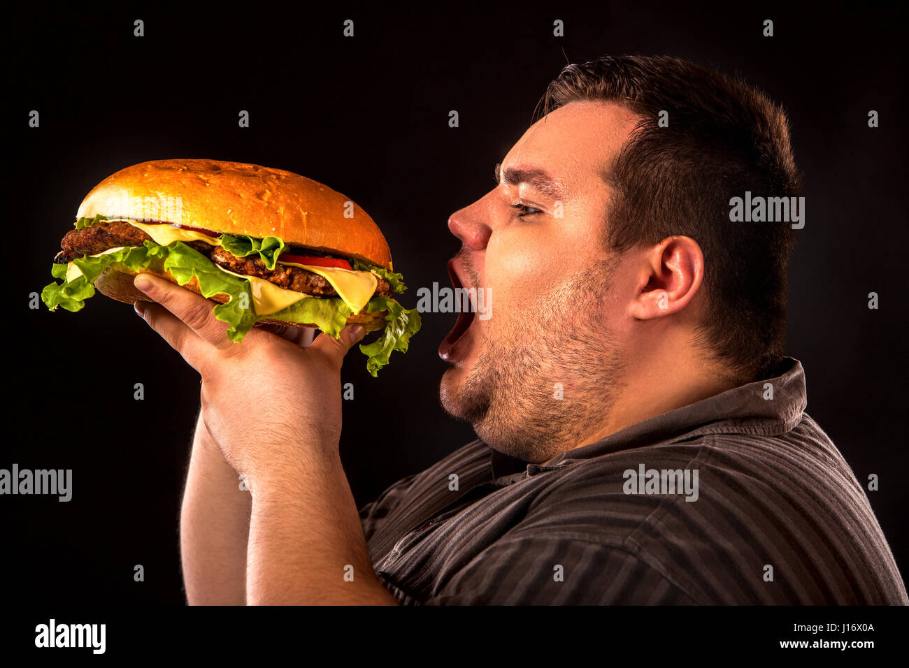 Fat man eating fast food hamberger. Breakfast for overweight person ...