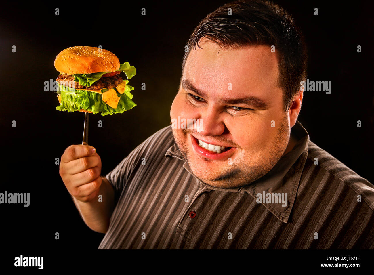 Fat man eating fast food hamberger. Breakfast for overweight person ...