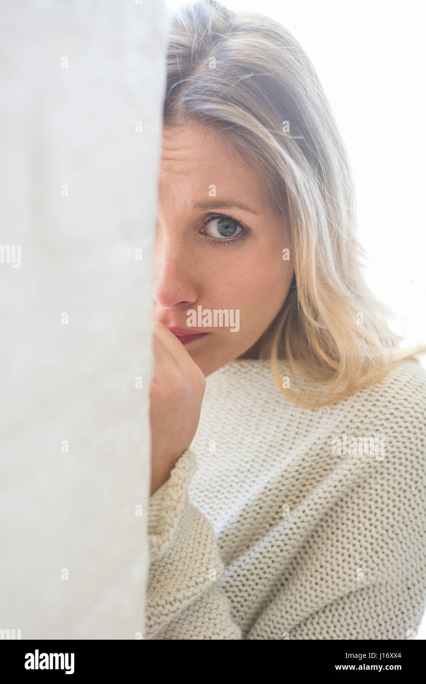 Young blond woman hiding behind the wall Stock Photo - Alamy