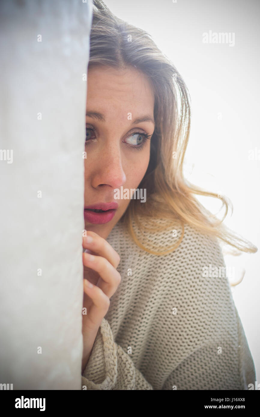 Young blond woman hiding behind the wall Stock Photo - Alamy