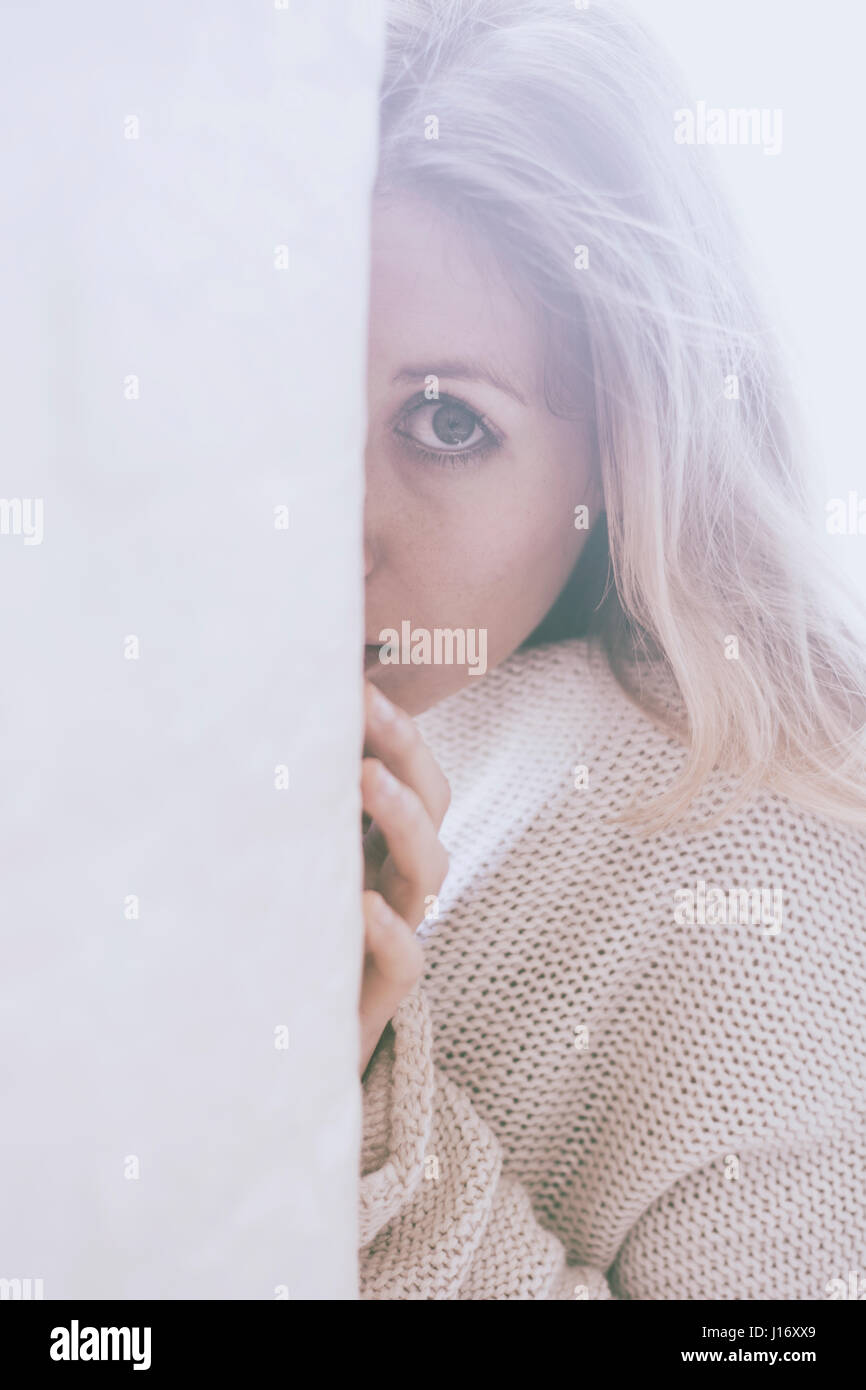 Young blond woman hiding behind the wall Stock Photo - Alamy