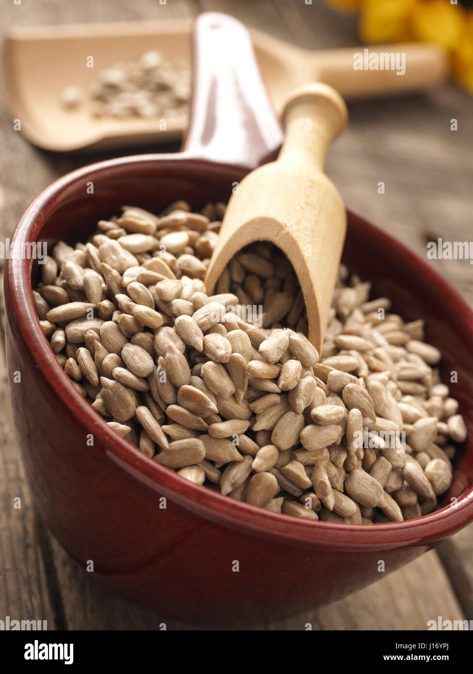 Raw sunflower seeds in a red bowl with a wooden spoon, healthy food or ...
