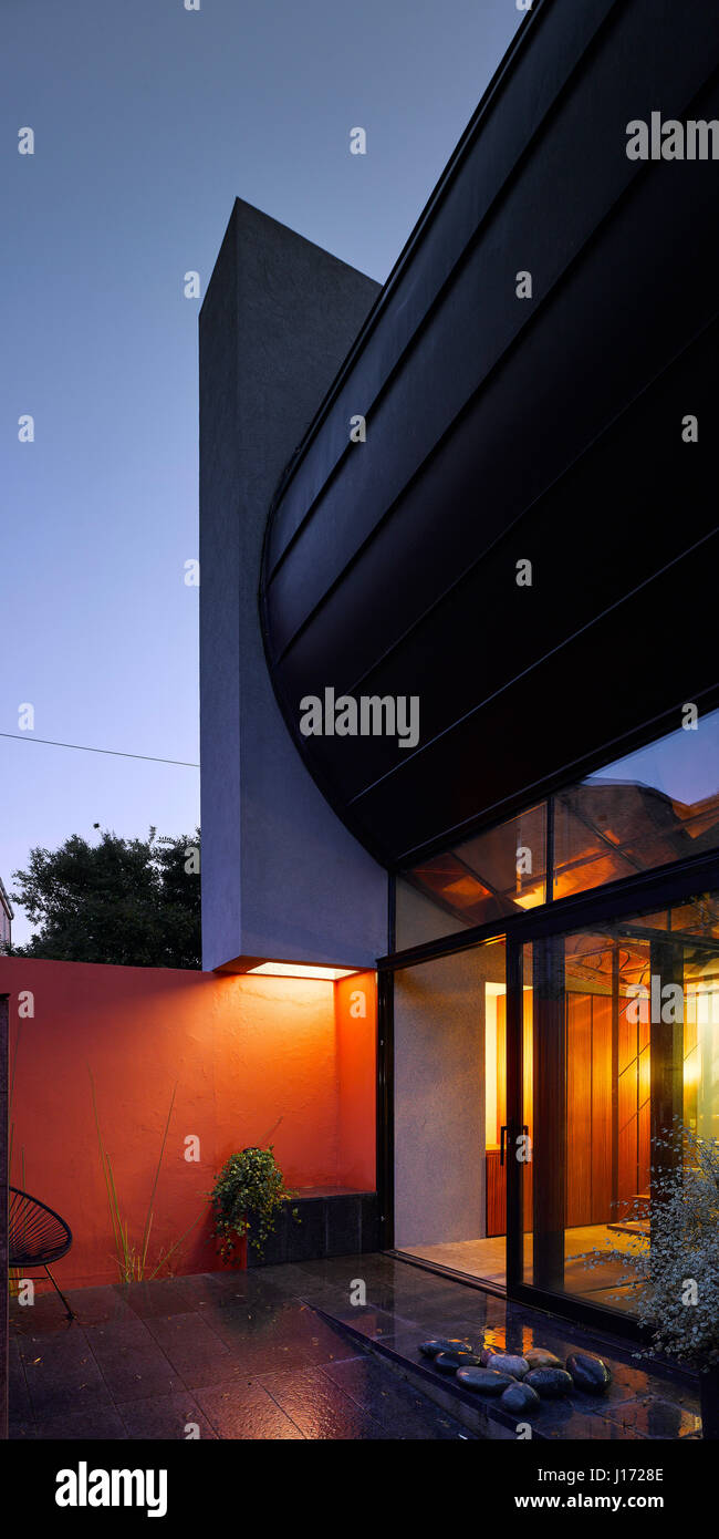 Exterior view of courtyard at dusk showing interior lights. K House ...