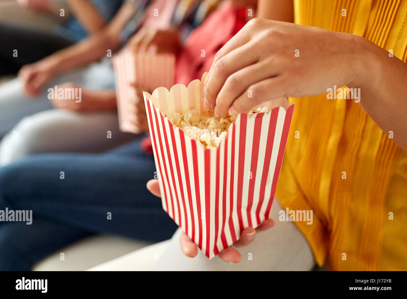 close up of happy friends eating popcorn at home Stock Photo - Alamy