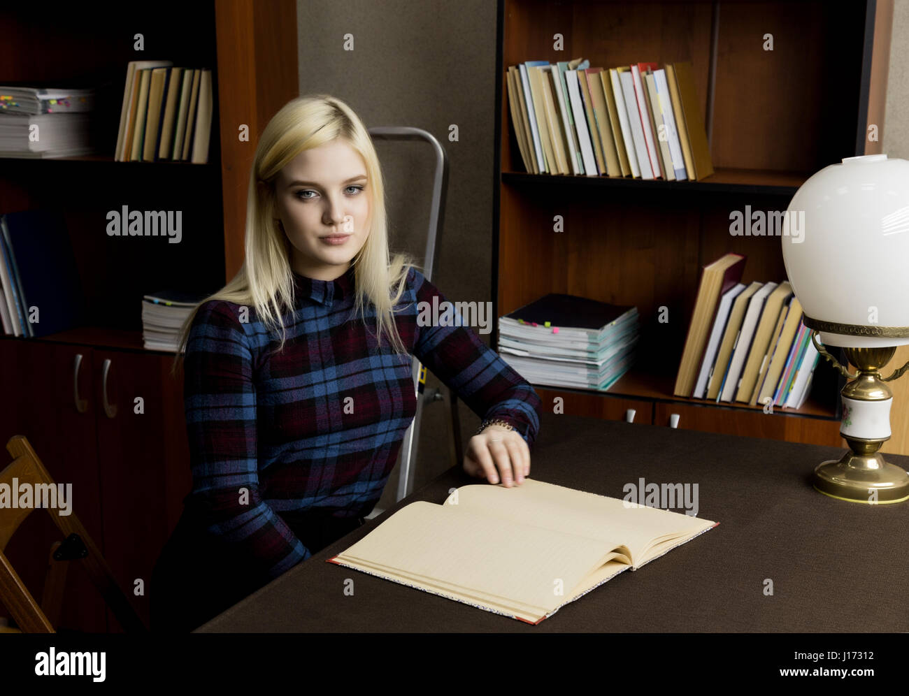 young woman reading a big book in library. bookshelves with books Stock ...