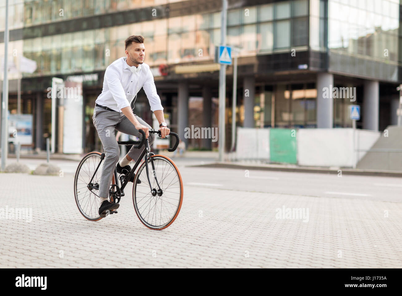 man with headphones riding bicycle on city street Stock Photo - Alamy