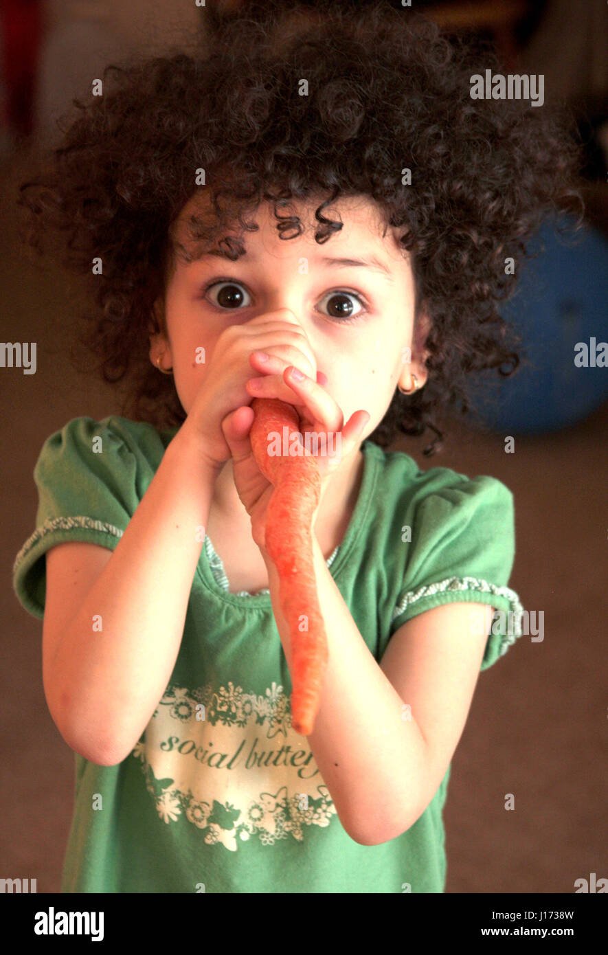 Cute little girl playing with long carrot; creative act; expressions ...