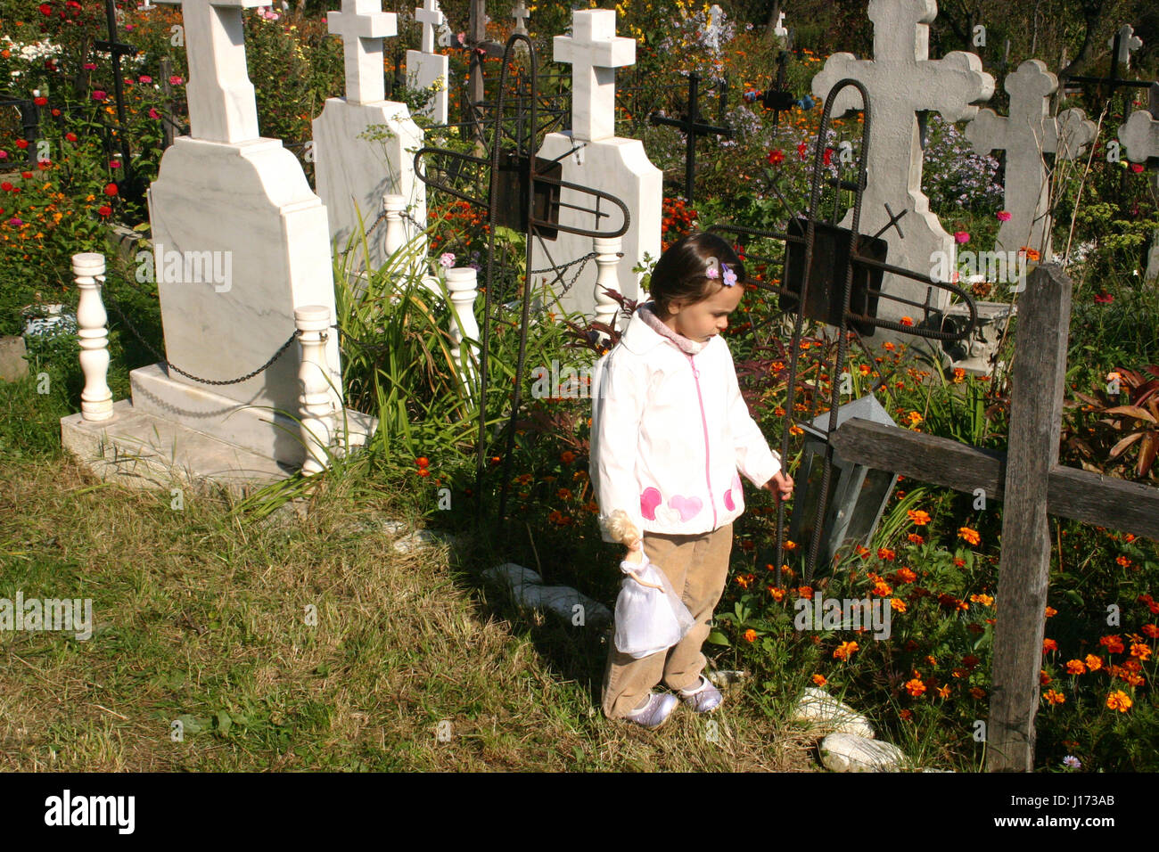 Little girl by graveyard in Orthodox cemetery in Romania Stock Photo ...