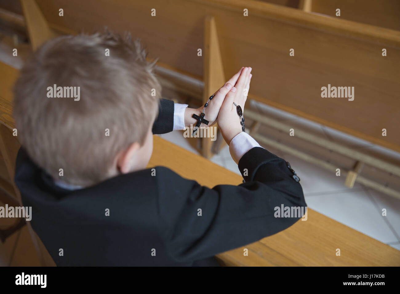 Boy praying with rosary during first holy communion in church Stock ...