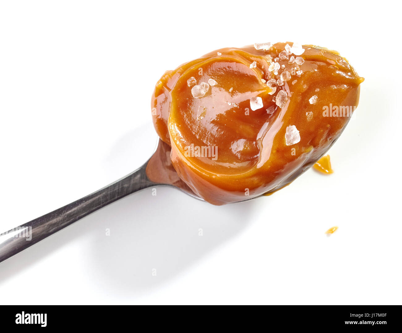spoon of soft homemade salted caramel isolated on white background, top ...