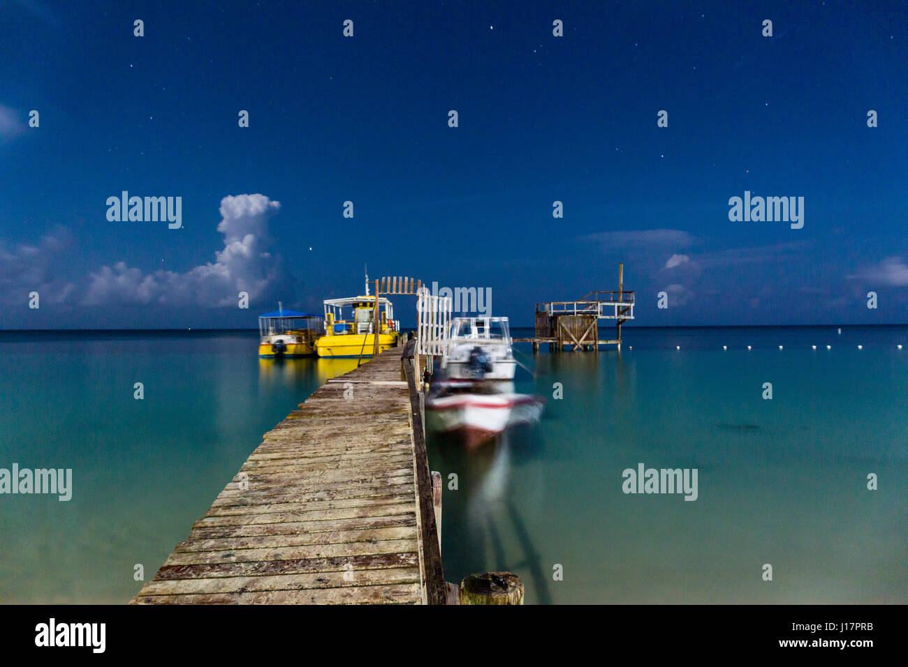 A full moon lights up the night sky above a rickety wooden pier in West ...