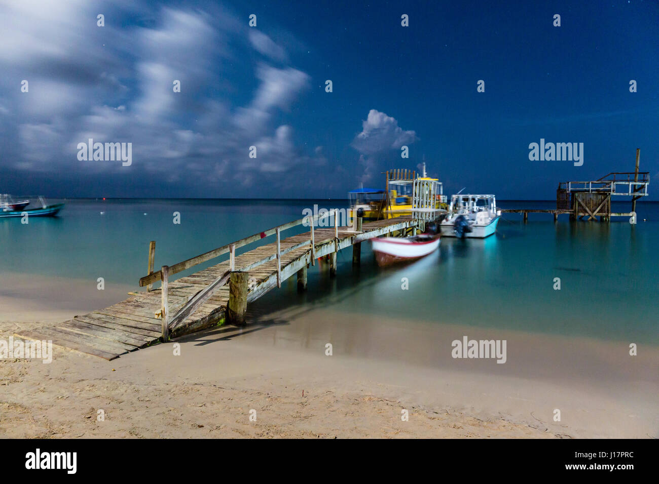 A full moon lights up the night sky above a rickety wooden pier in West ...