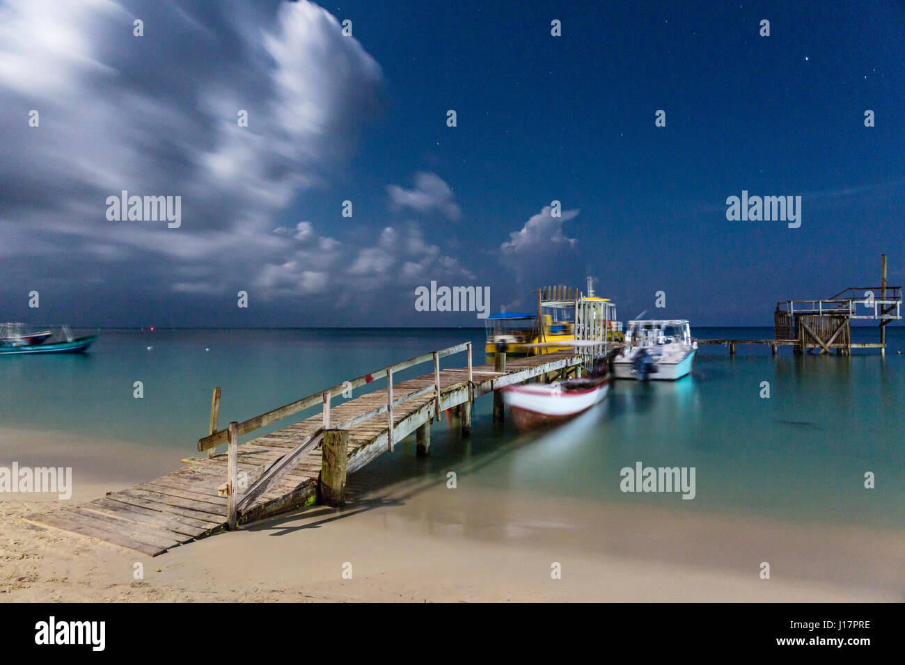 A full moon lights up the night sky above a rickety wooden pier in West ...