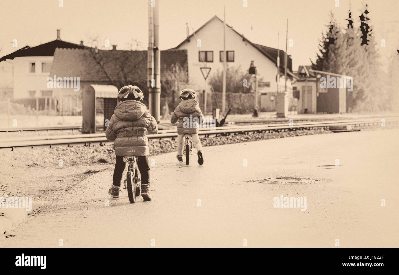 Twins children riding balance bikes on the road with helmet. Young ...