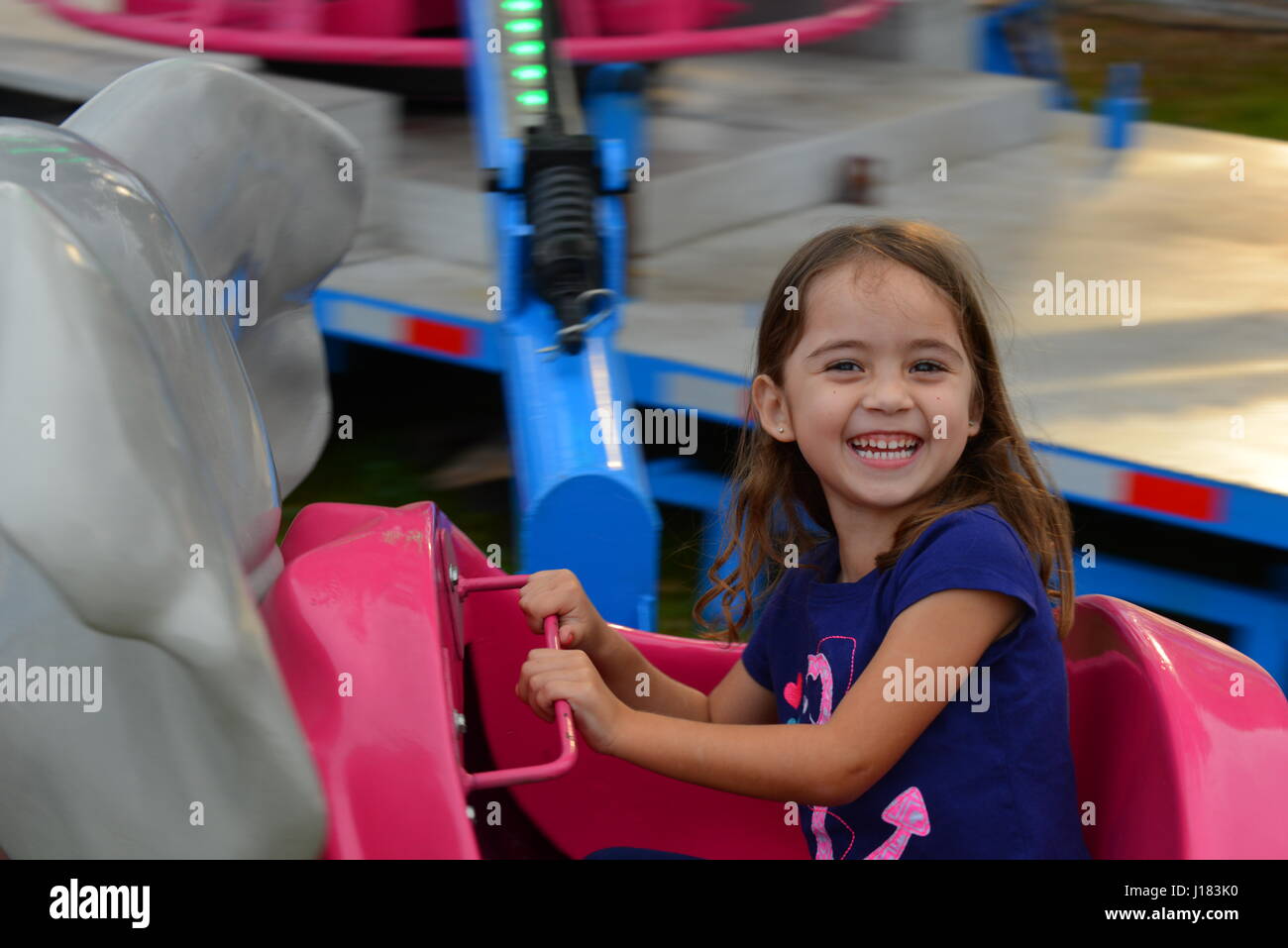 young girl at local fair on ride smiling Stock Photo - Alamy