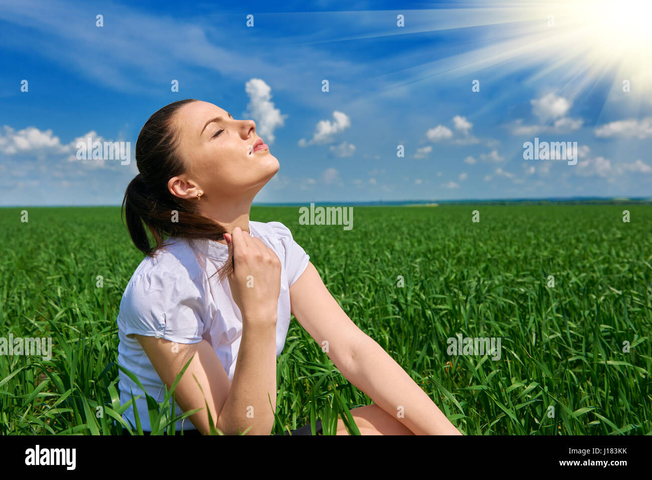 Business woman relaxing in green grass field outdoor under sun ...