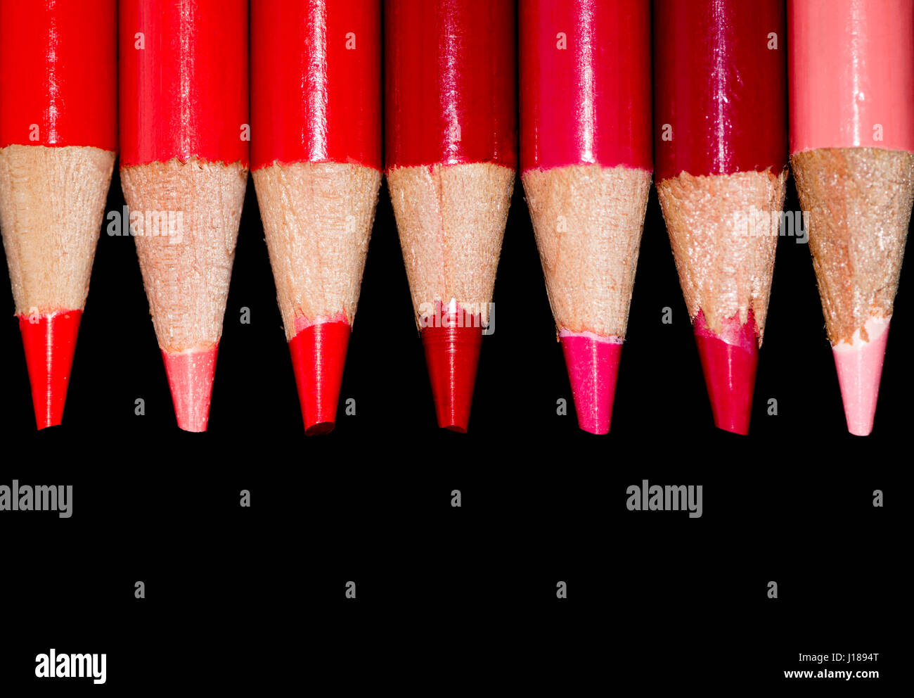Seven red pencils of various hues and shades including pink, lined up ...