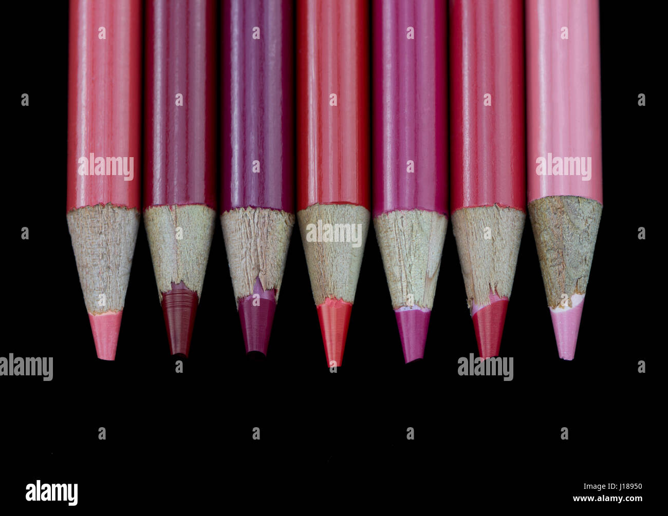 Seven red pencils of various hues and shades including pink, lined up ...