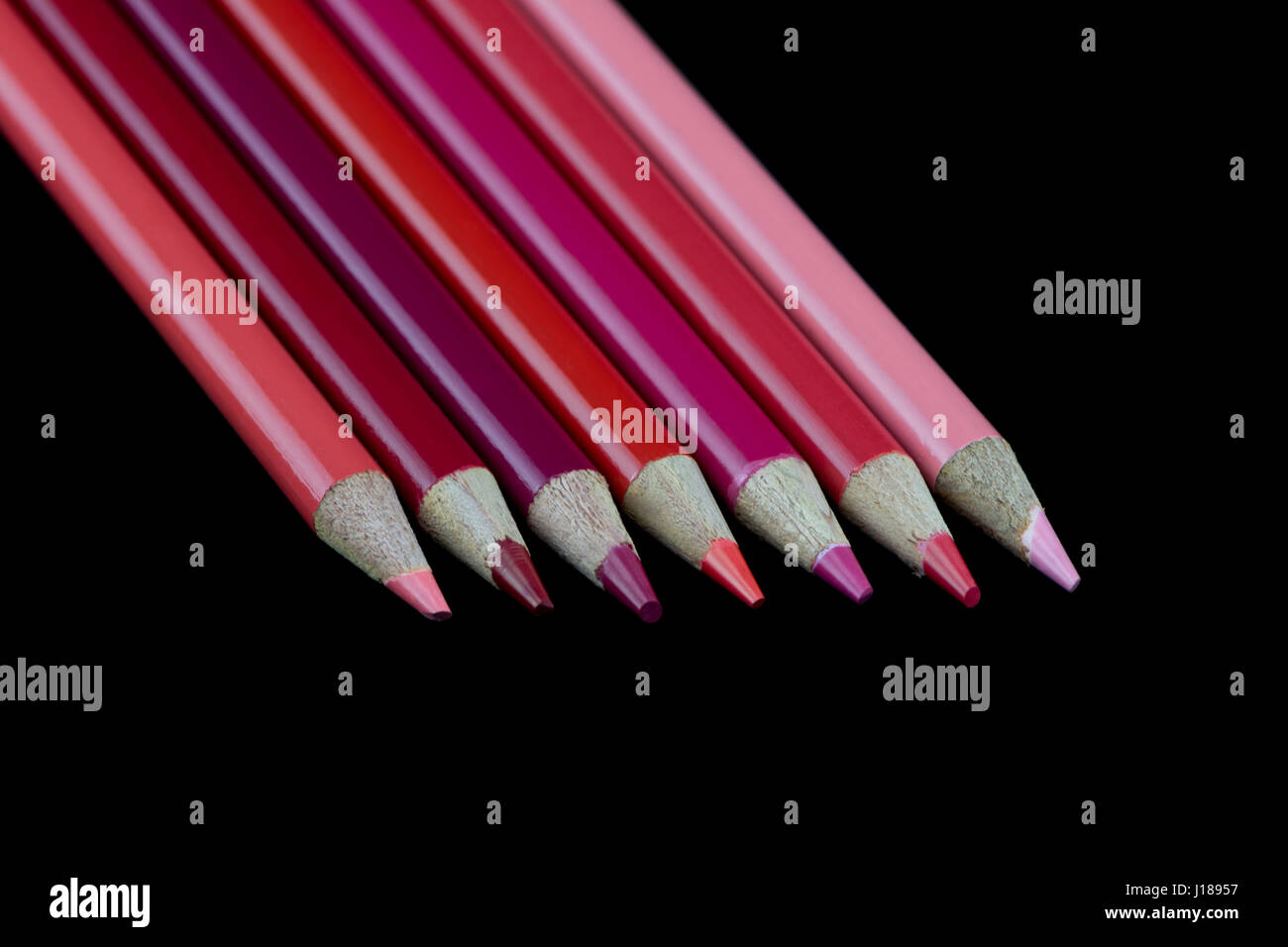 Seven red pencils of various hues and shades including pink, lined up ...