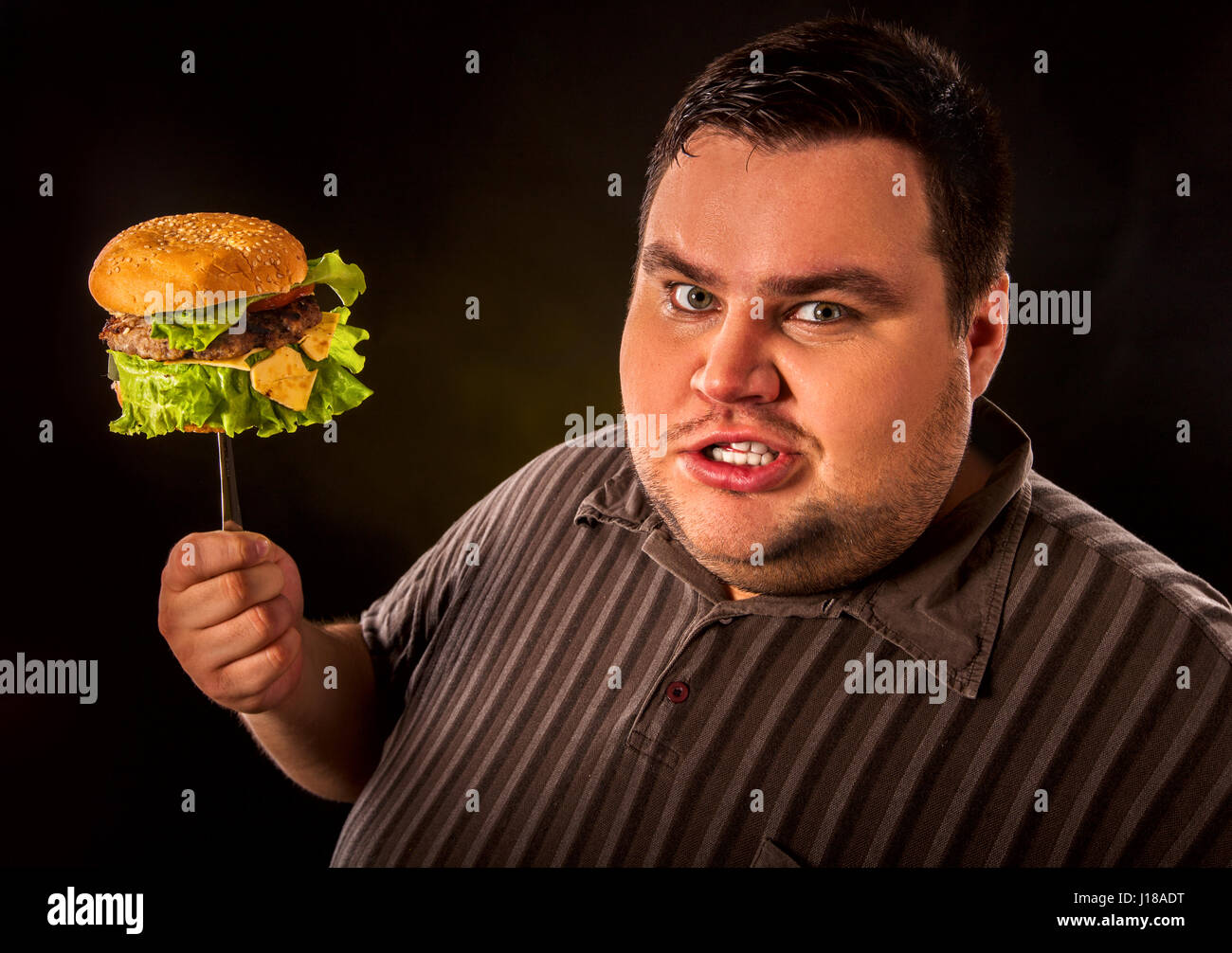 Fat man eating fast food hamberger. Breakfast for overweight person ...