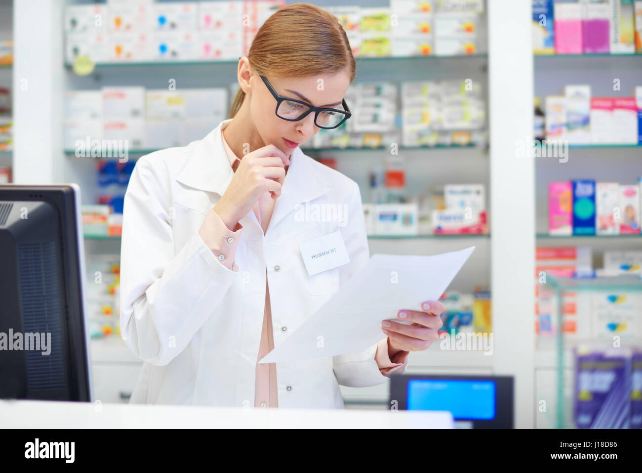 Female pharmacist checking documents at drugstore Stock Photo - Alamy