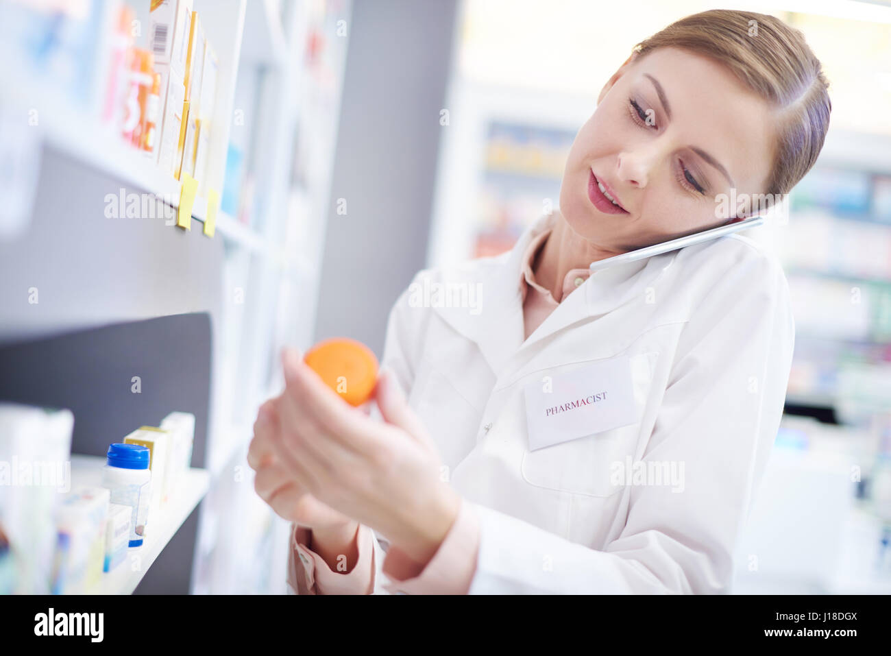 Female pharmacist on phone call reaching medication Stock Photo - Alamy