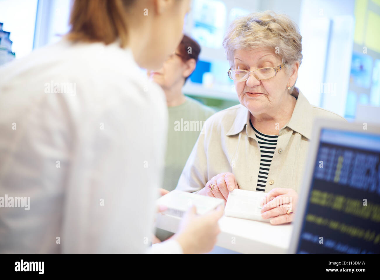 Senior customer at cash register with pharmacist Stock Photo - Alamy