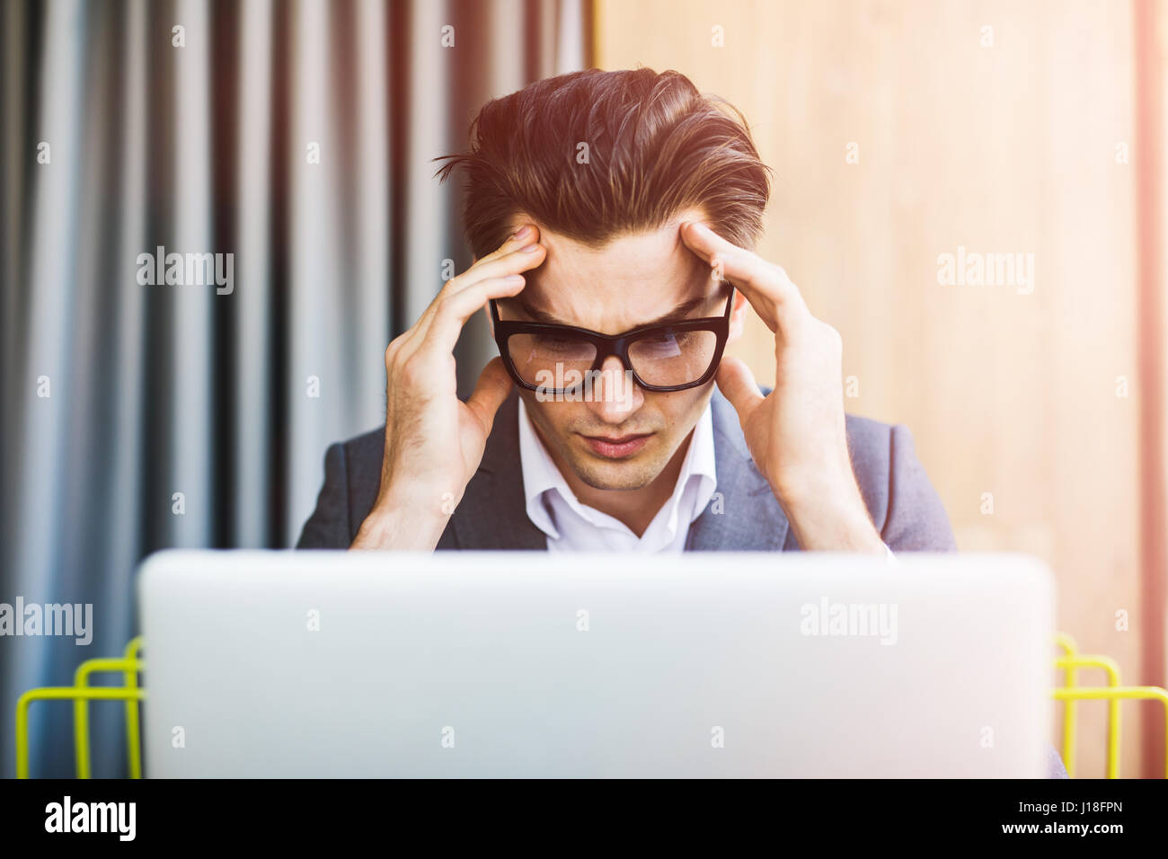 Stressed businessman sitting in front of laptop Stock Photo - Alamy