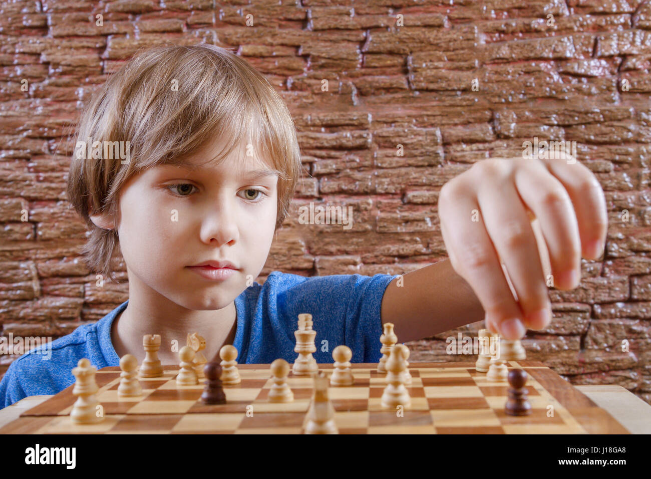 Portrait of a little caucasian boy playing chess and making next move ...