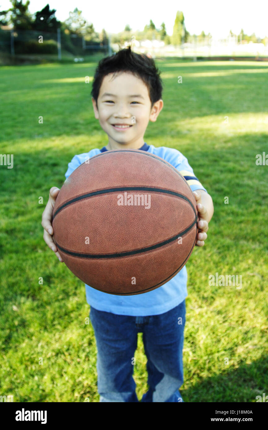 A happy boy handing a basketball (shallow DOF, focus on the ball Stock ...
