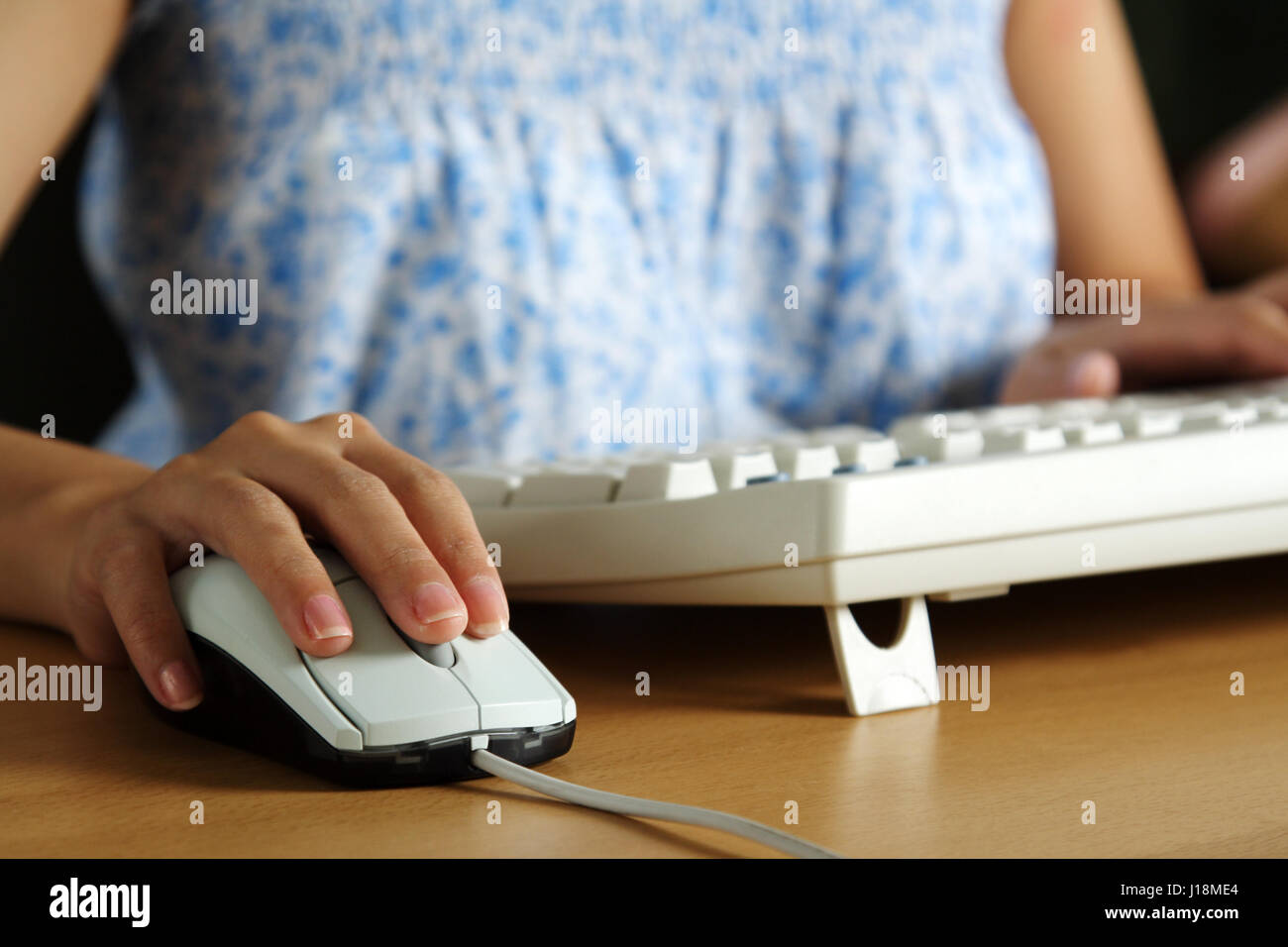 A woman using mouse and typing on keyboard Stock Photo - Alamy