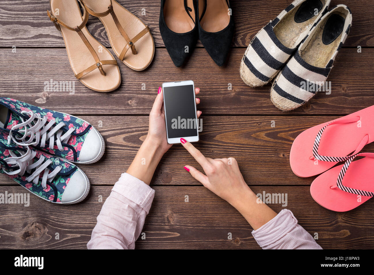 Female shoes collection on wooden table with woman's hands using smart ...