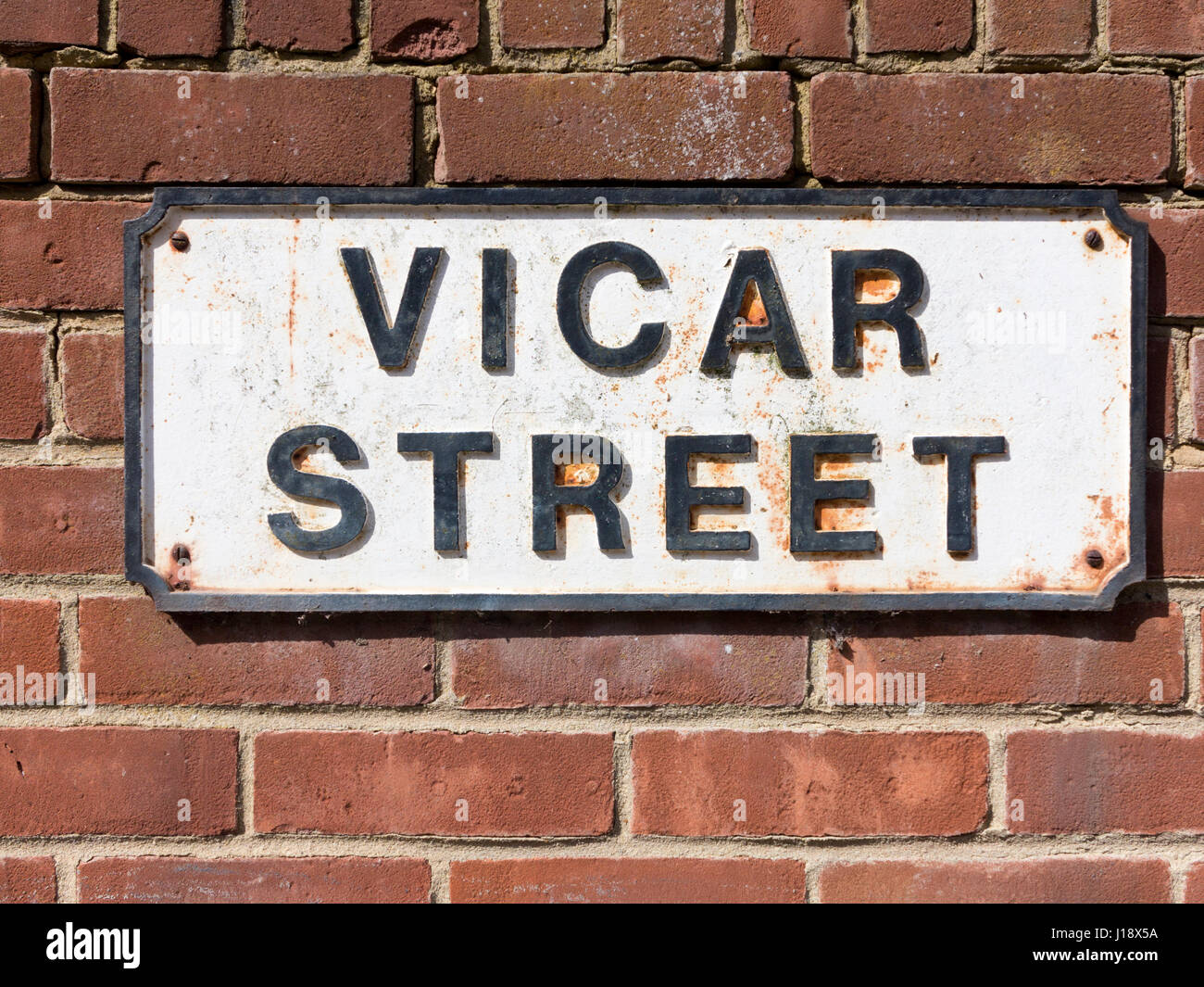 A metal, black and white road sign for 'Vicar Street' mounted on a red ...