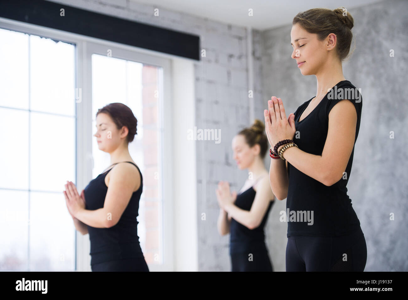 Female trainer with class standing in namaste pose at yoga class Stock ...