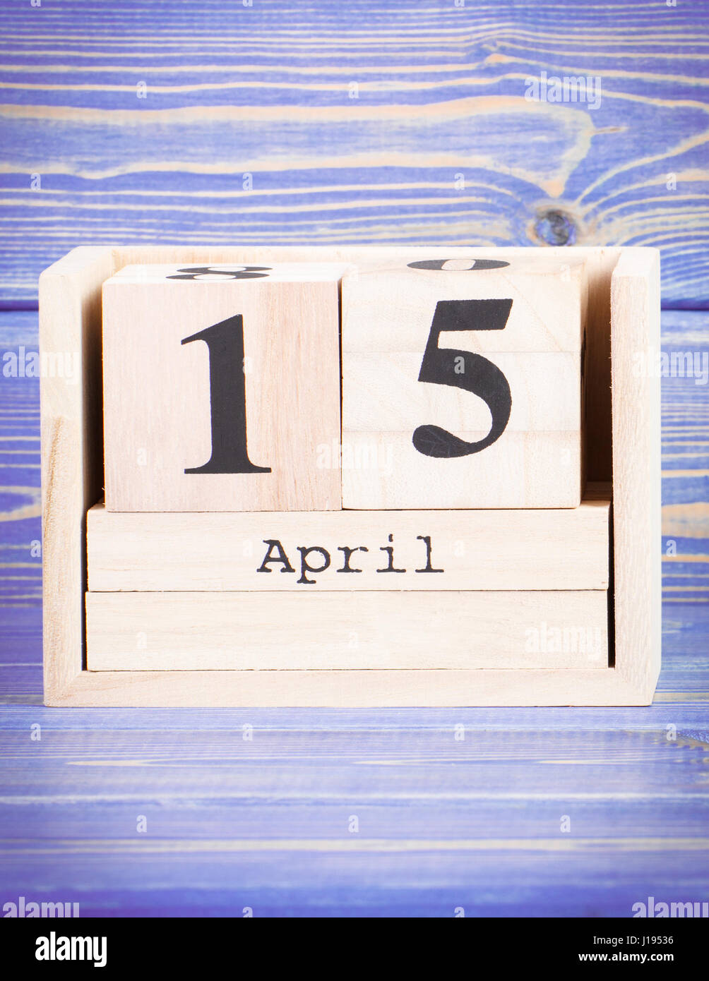 April 15th. Date of 15 April on wooden cube calendar, purple board as ...