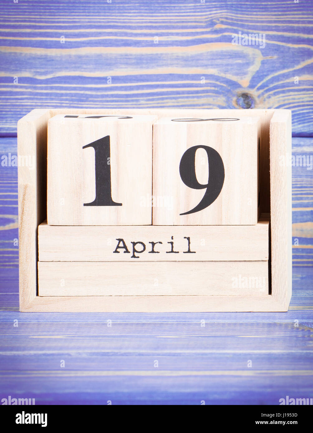April 19th. Date of 19 April on wooden cube calendar, purple board as ...