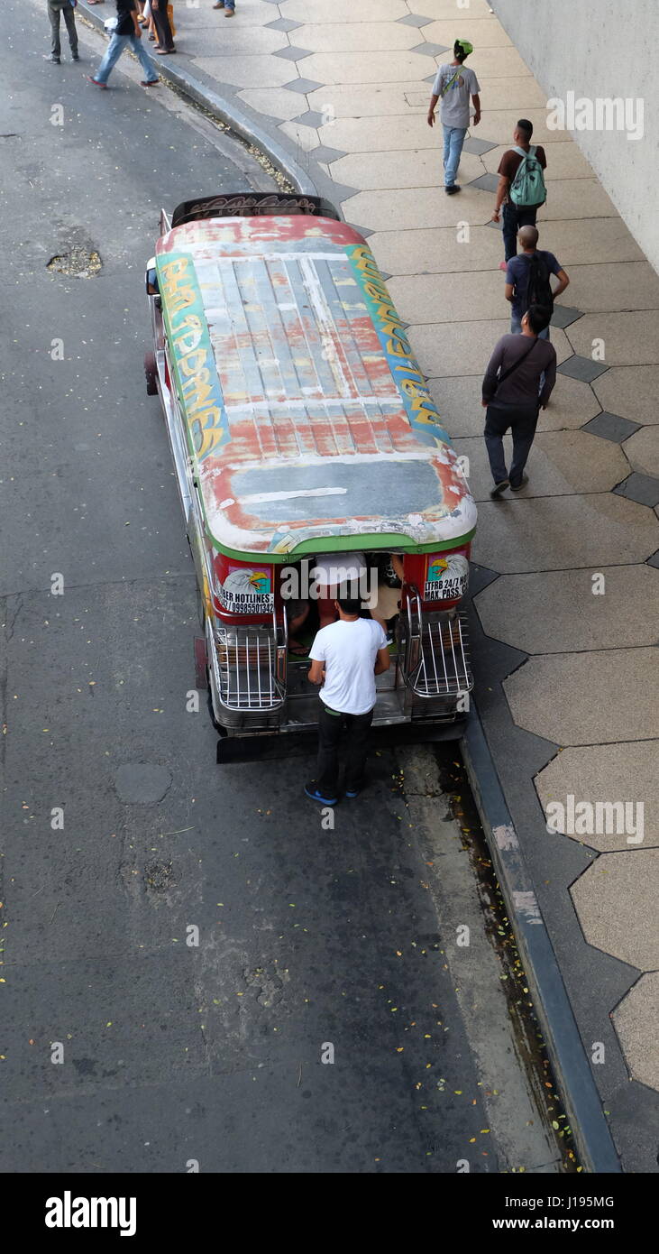 A passenger climbing onto a Jeepney, a small bus which is a popular ...