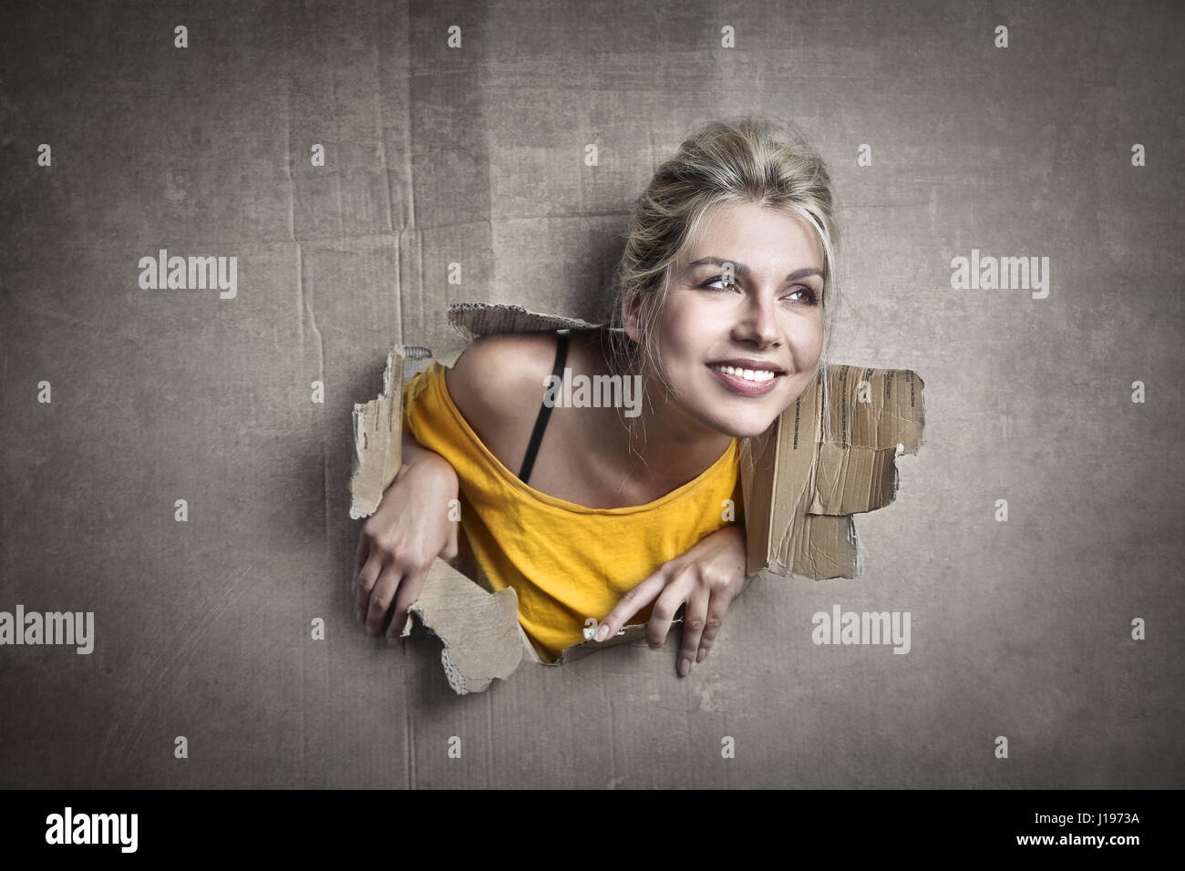Blond woman breaking through paper Stock Photo - Alamy