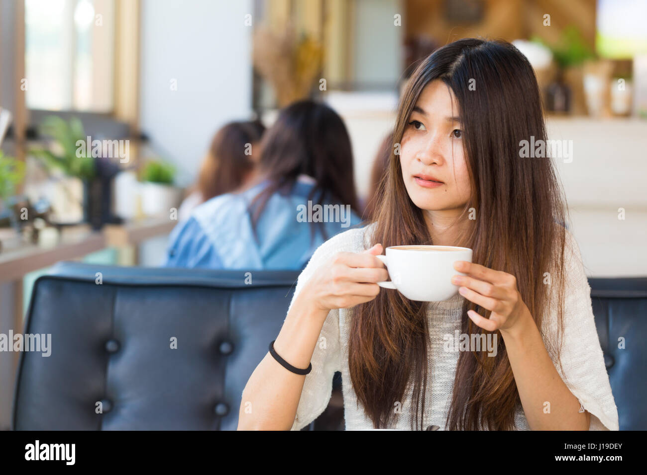 Young charming asian student woman hold cup of coffee drink in cafe ...