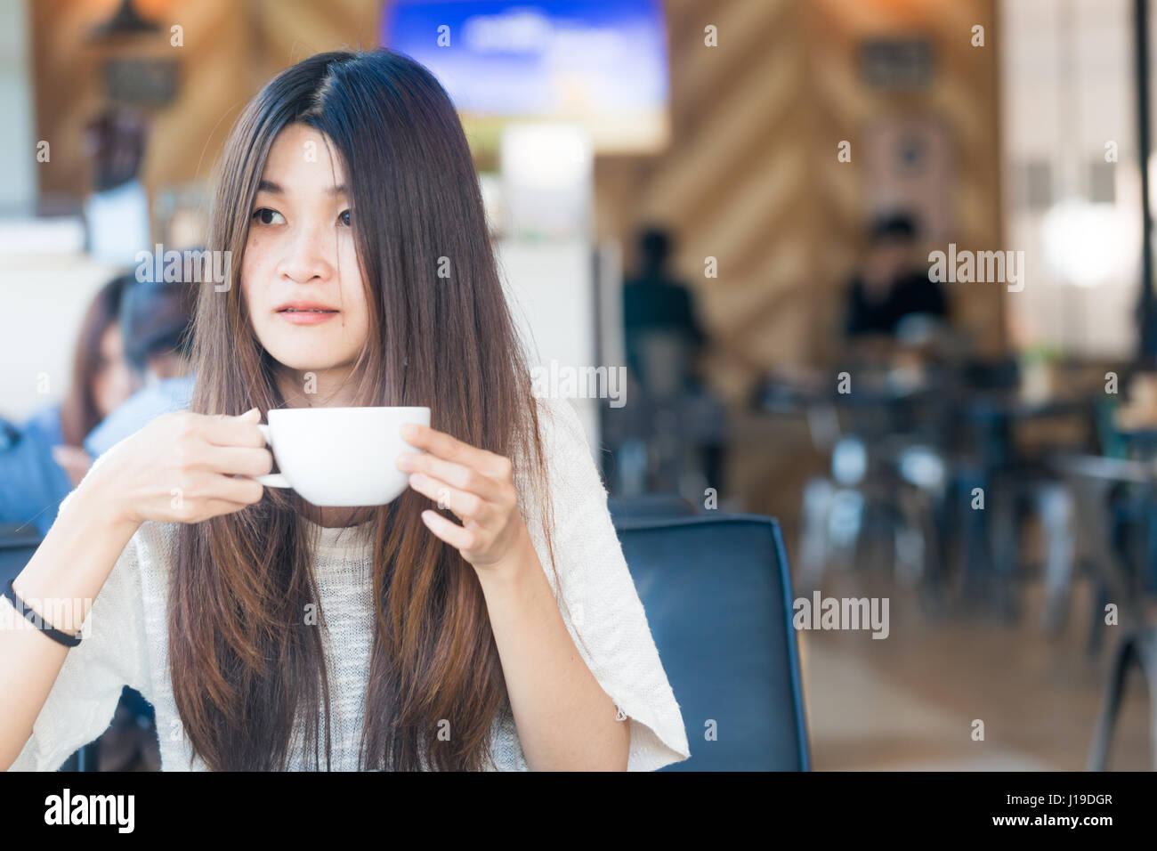 Young charming asian student woman hold cup of coffee drink in cafe ...